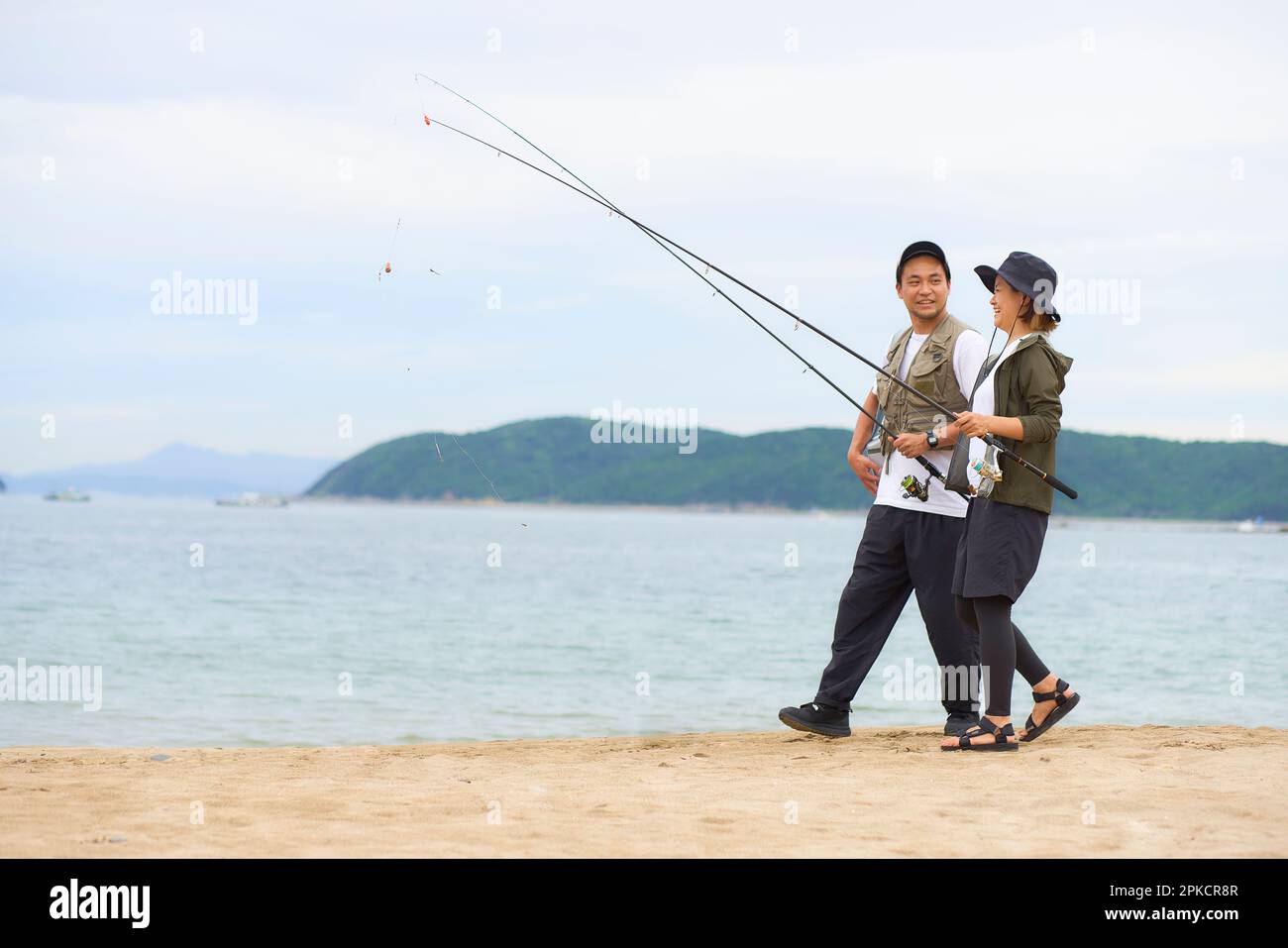 Men and women walking on the beach with fishing gear Stock Photo - Alamy