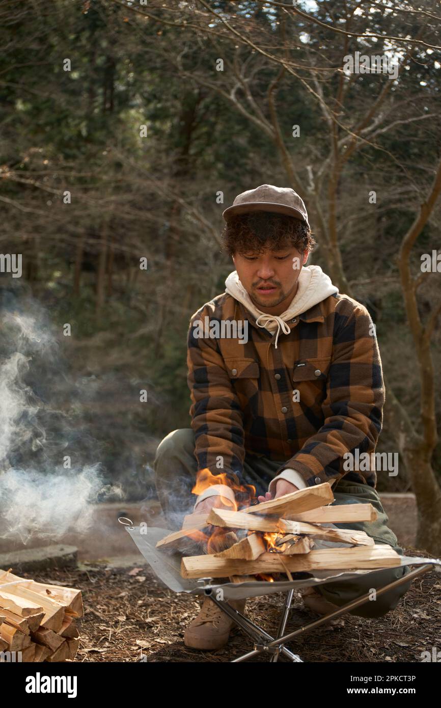 Man building a fire in a winter campsite Stock Photo - Alamy