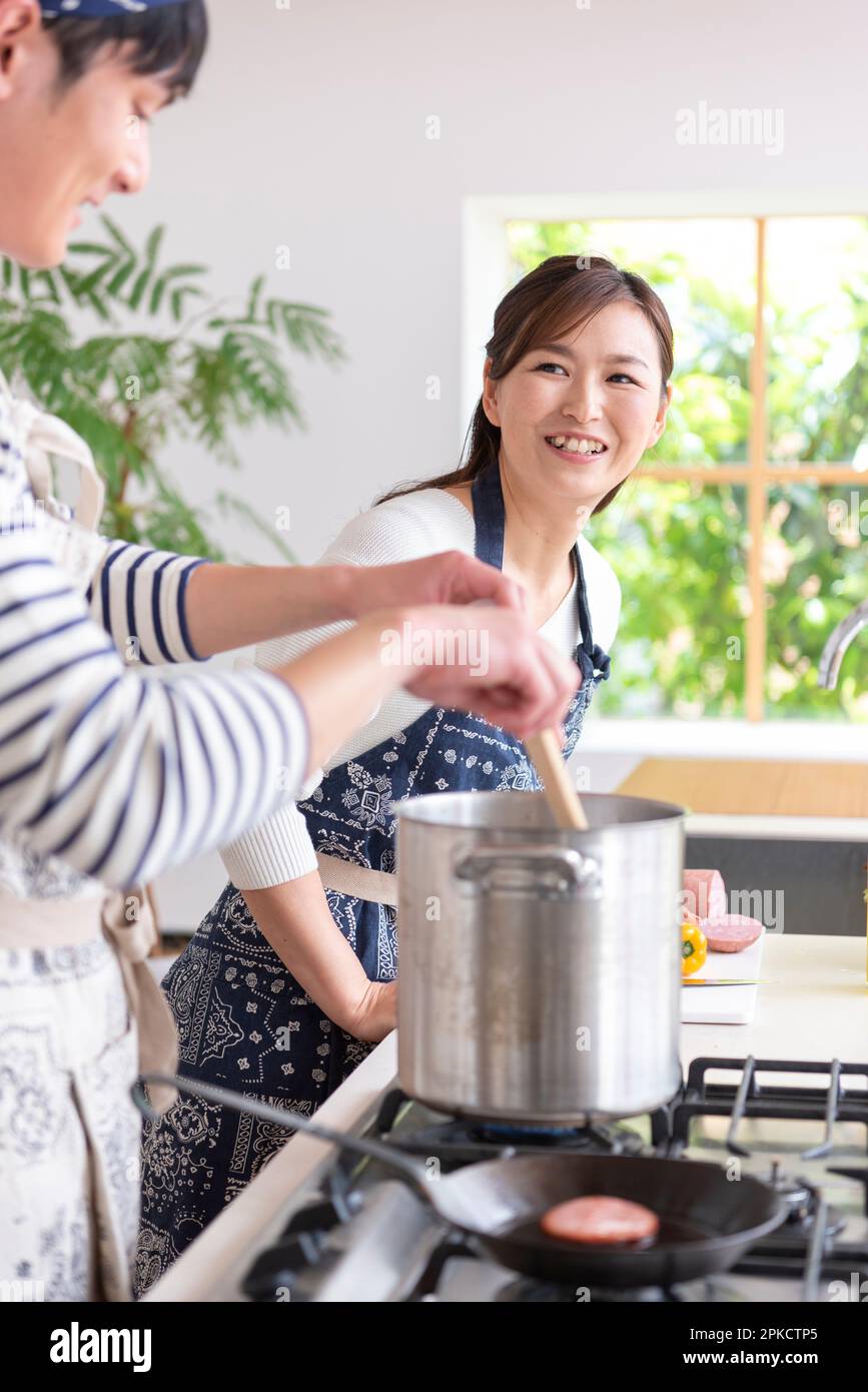 Couple in their 30s cooking in the kitchen Stock Photo - Alamy