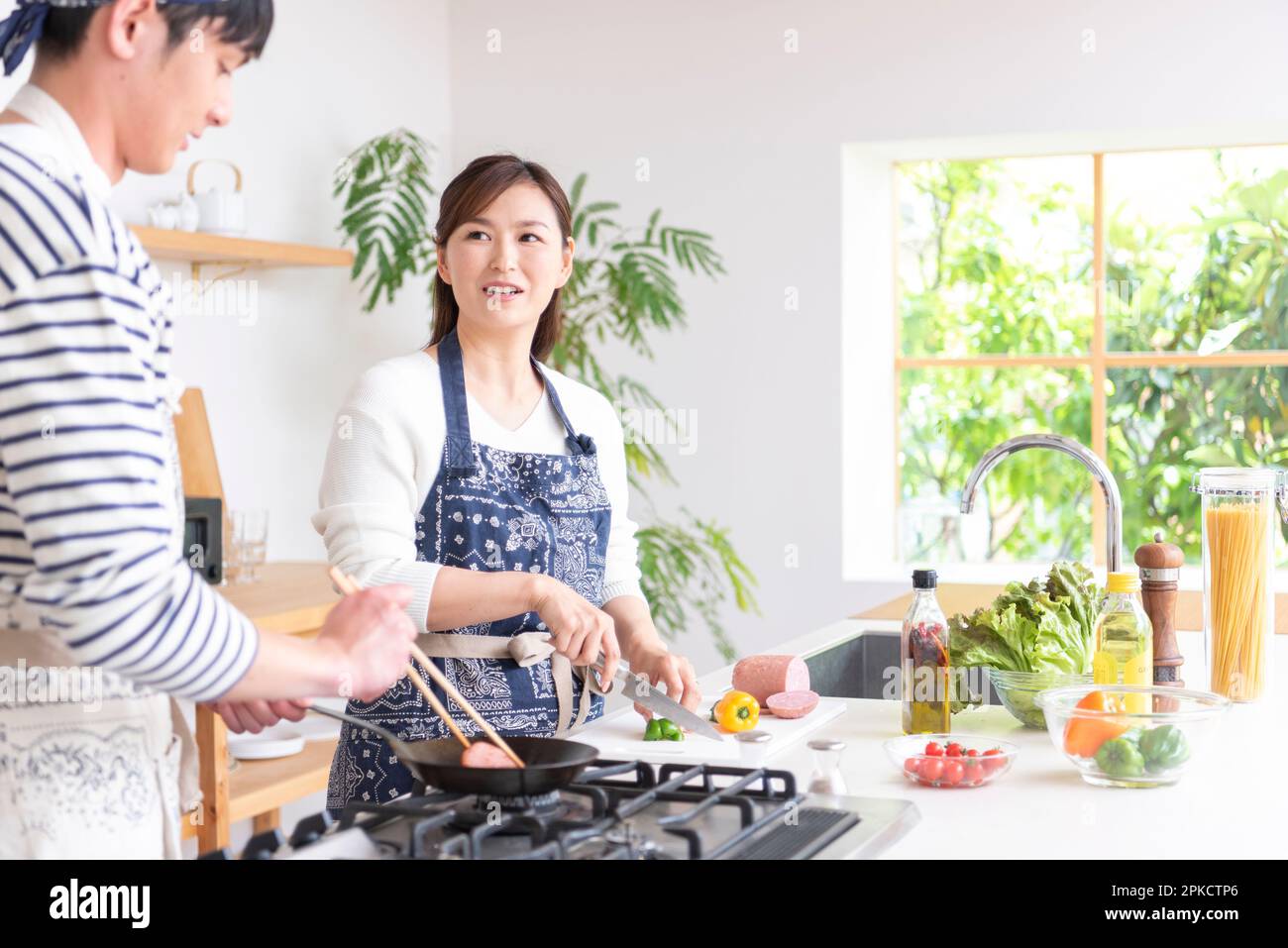 Couple in their 30s cooking in the kitchen Stock Photo - Alamy