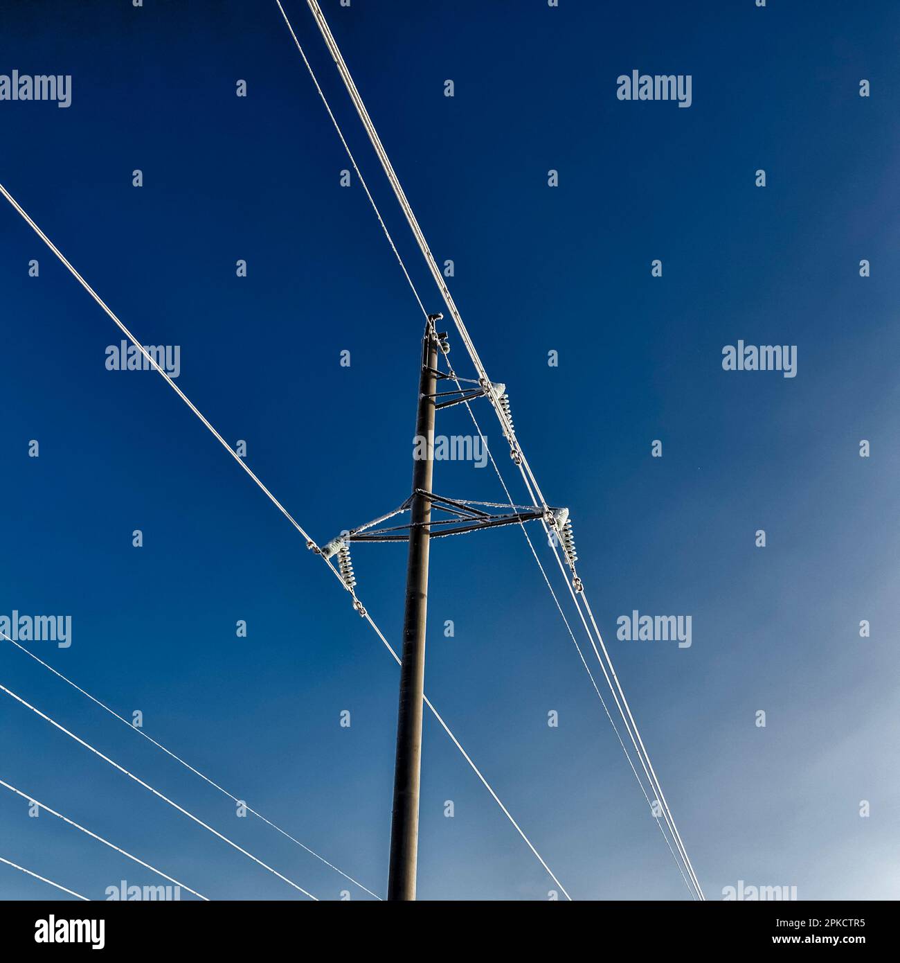 High-voltage wires and poles are covered with frost on a frosty winter ...