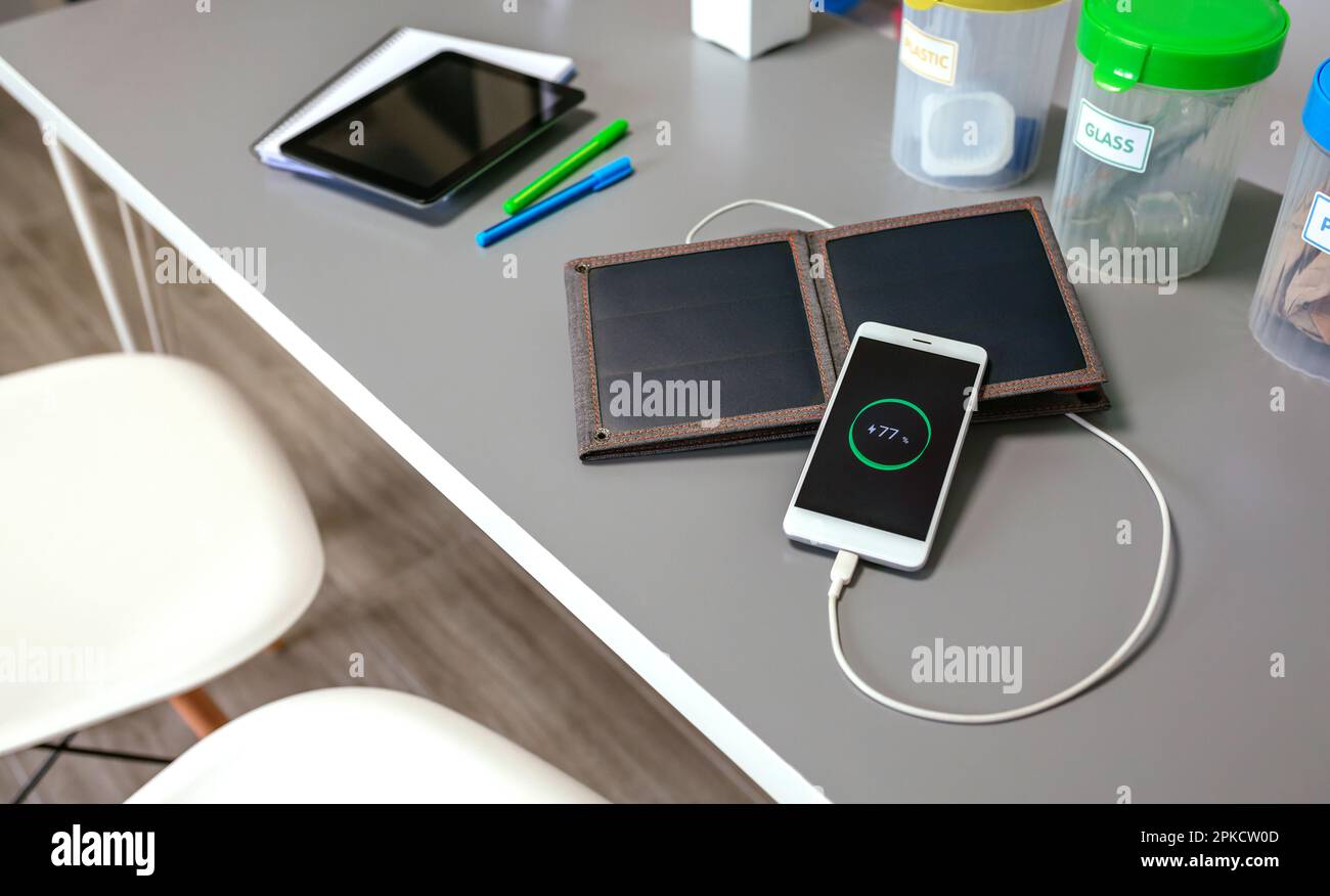 Close up of mobile phone charging battery with portable solar panel and ...