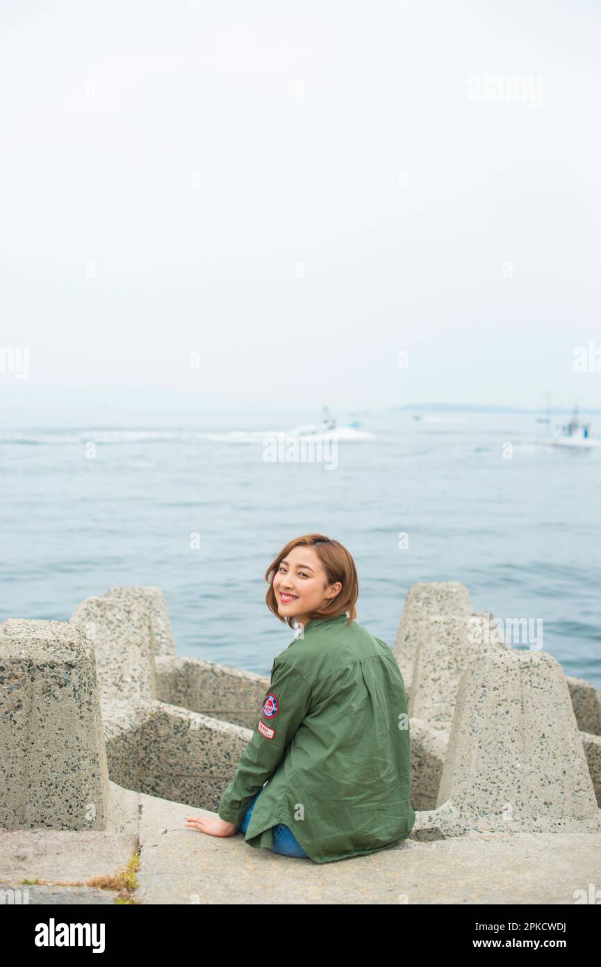 Woman sitting on the quay at the tetrapod in the harbor Stock Photo - Alamy