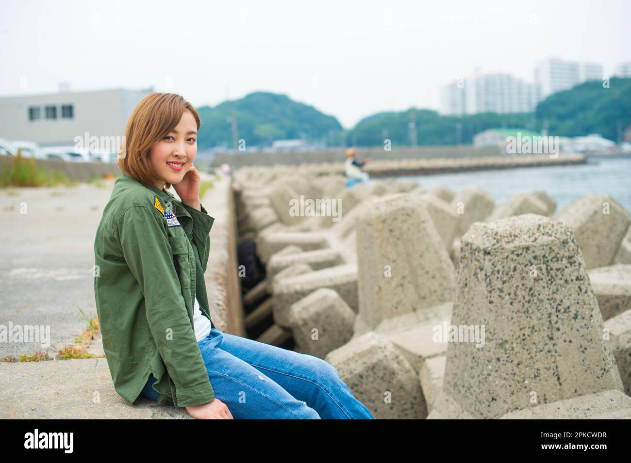 Woman sitting on the quay of the tetrapod in the harbor Stock Photo - Alamy