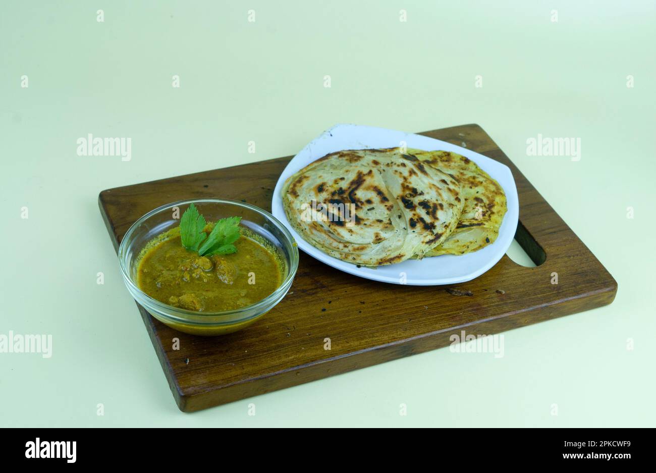 roti canai and curry sauce in white plate with served on the wooden ...