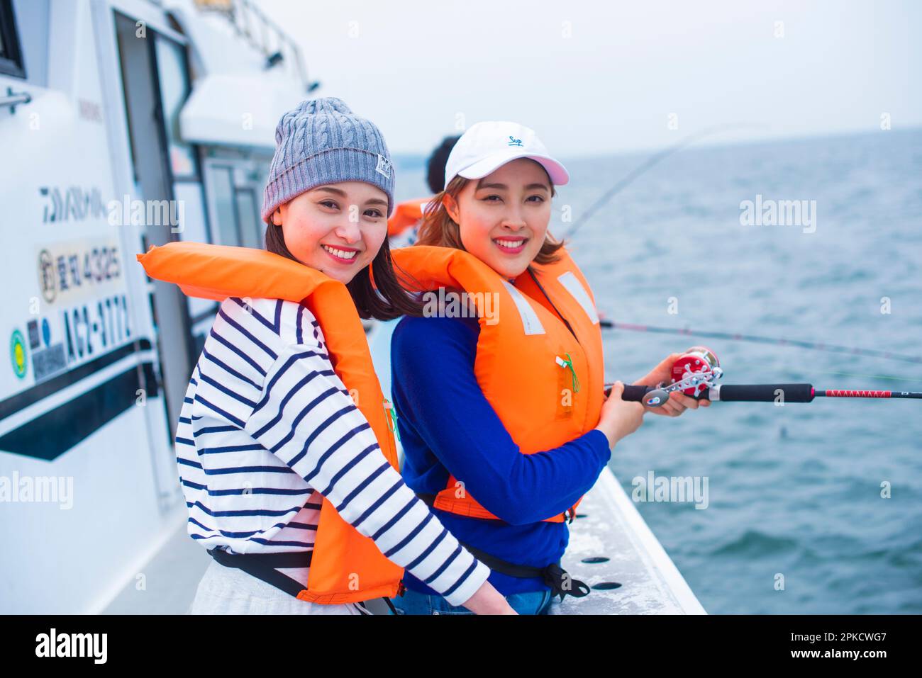 Two men and a woman in their 20s fishing in the sea by boat Stock Photo ...
