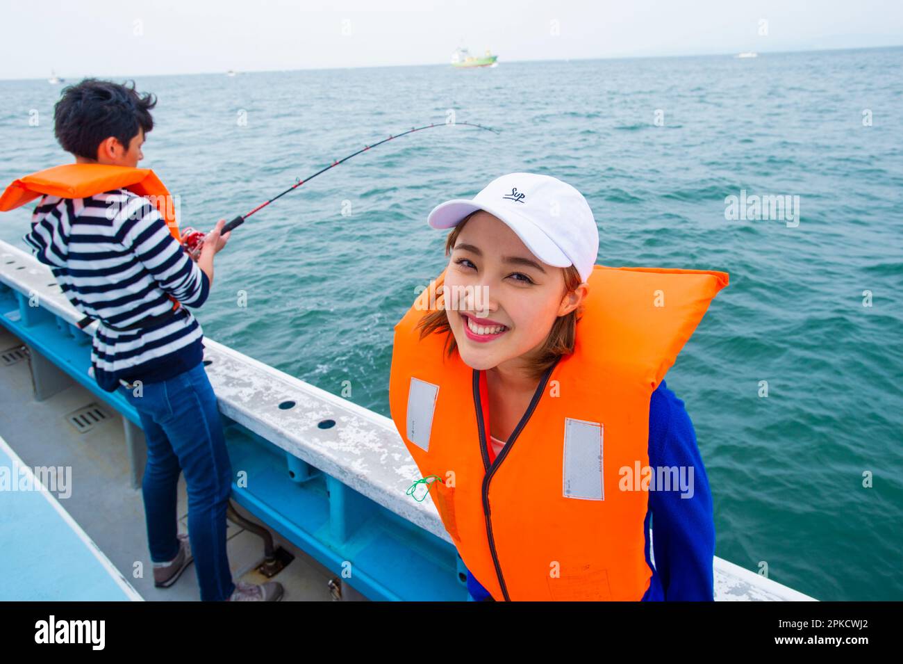Two men and a woman in their 20s fishing in the sea by boat Stock Photo ...