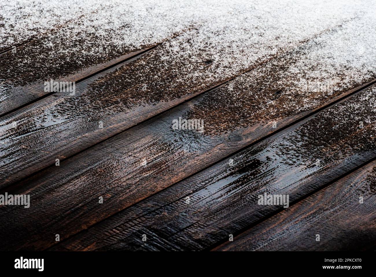 Snow melts on the wooden floor of the open veranda of a private house ...