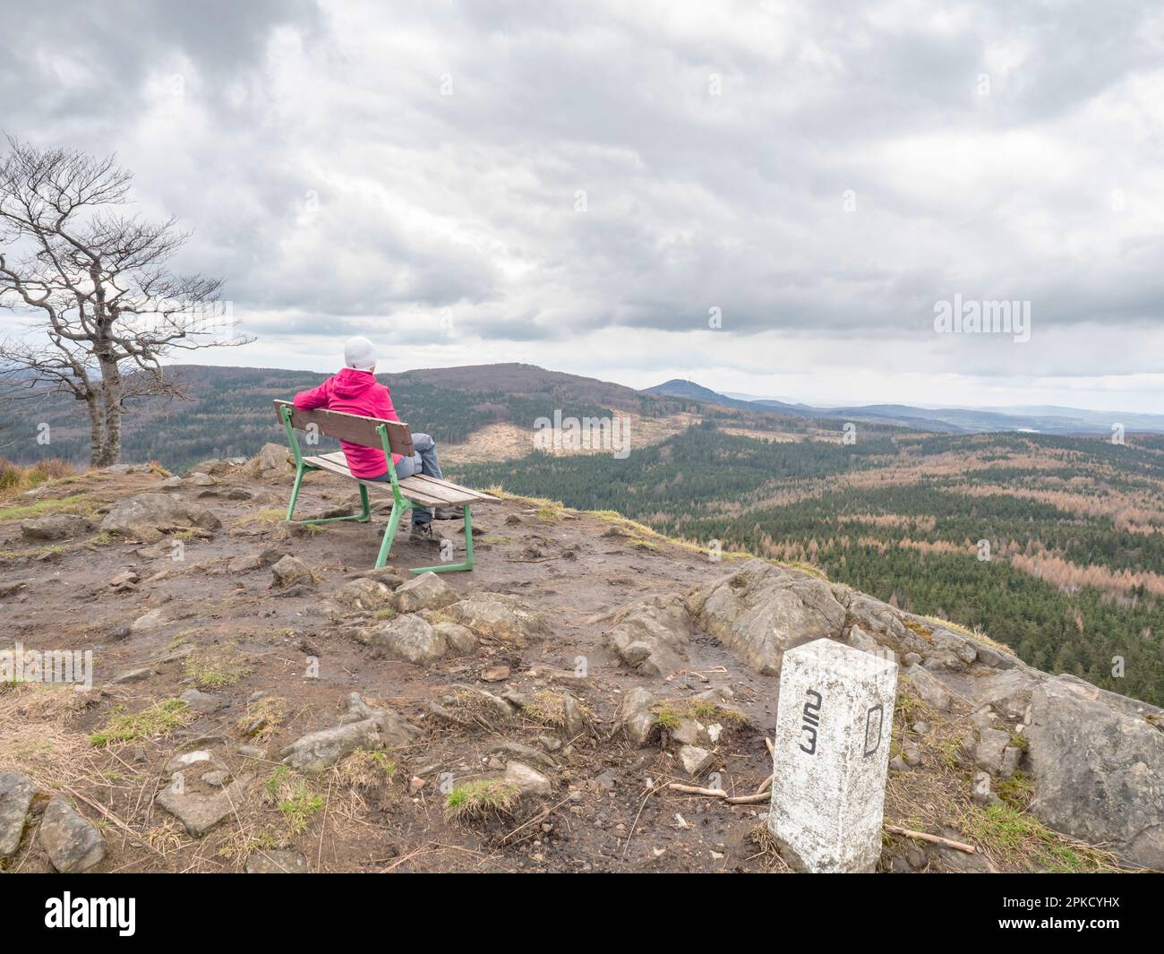 Tourist woman sin on bench at Lusitian mountain peak in pink warm ...