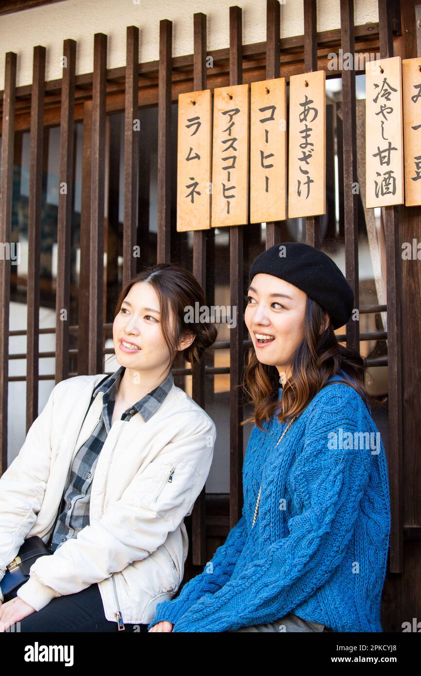 Two women taking a rest in front of a store at a tourist attraction ...