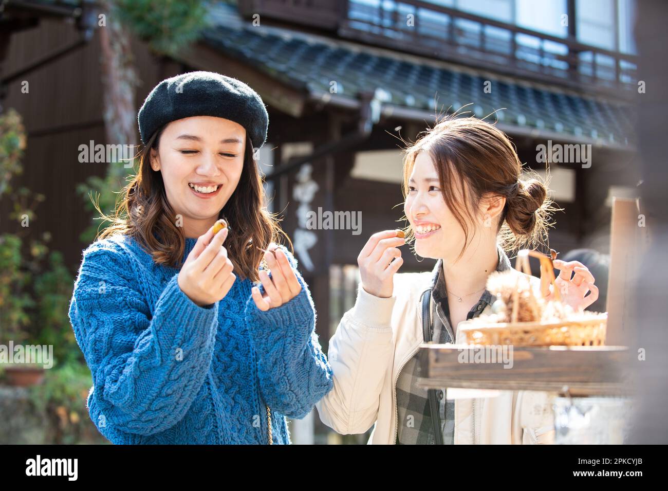 Two women eating chestnuts at a store in a tourist resort Stock Photo ...