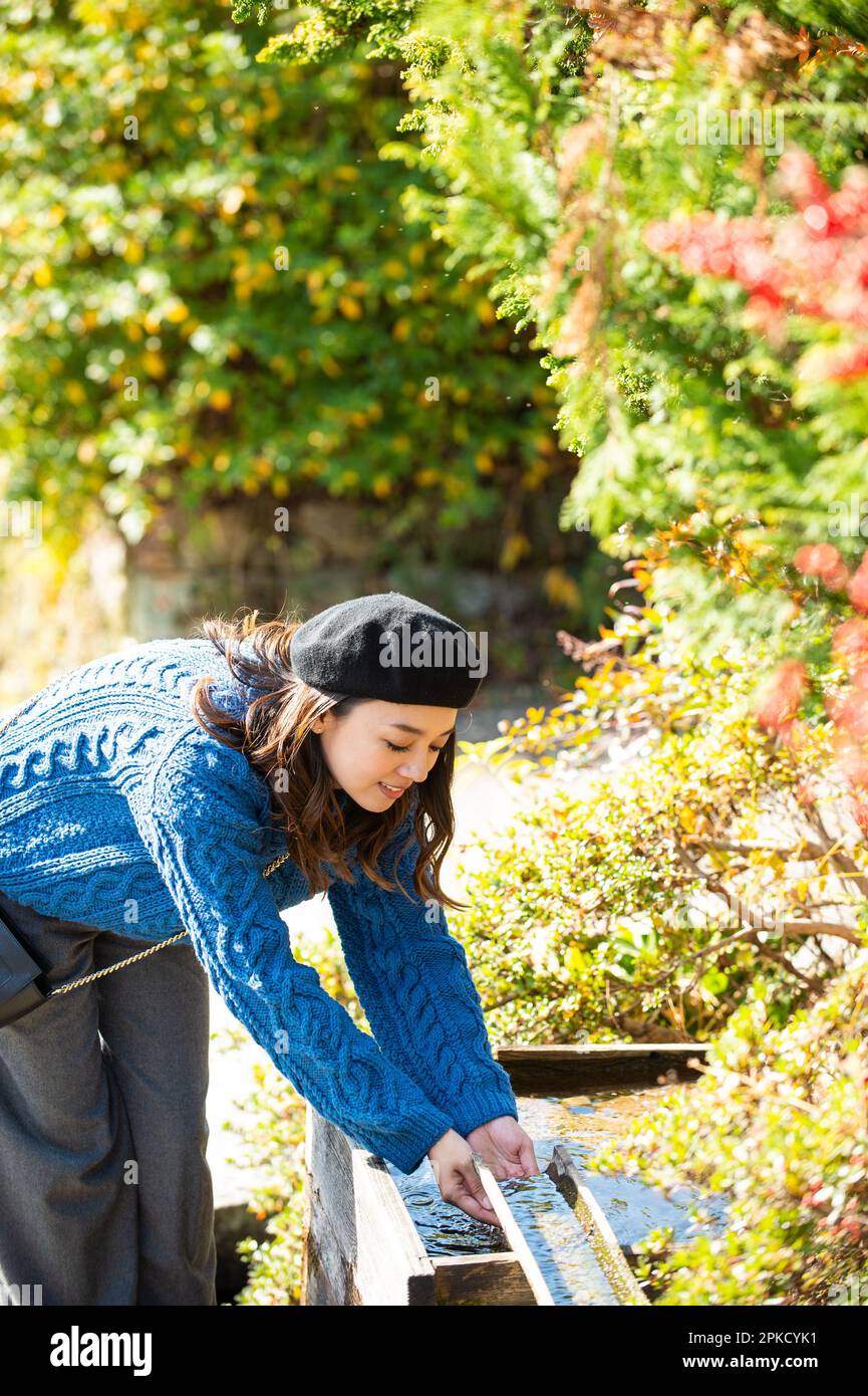 Woman washing her hands with spring water while strolling in a tourist ...