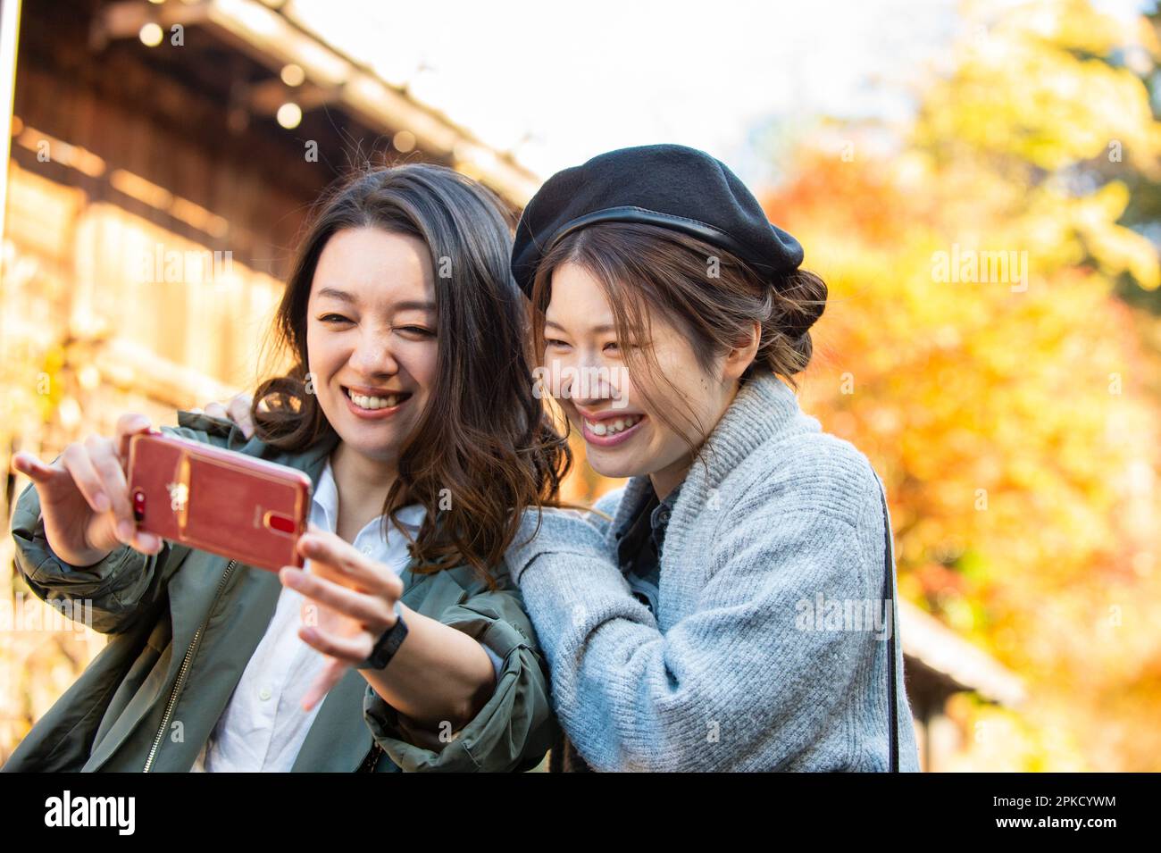 Two women taking photos in an autumn inn town Stock Photo - Alamy