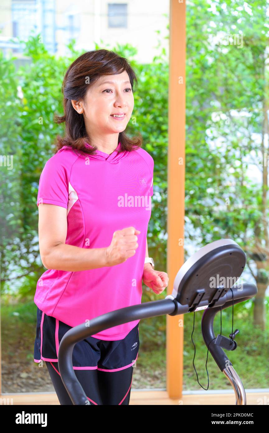 A middle-aged woman exercising with a machine at her own home Stock ...