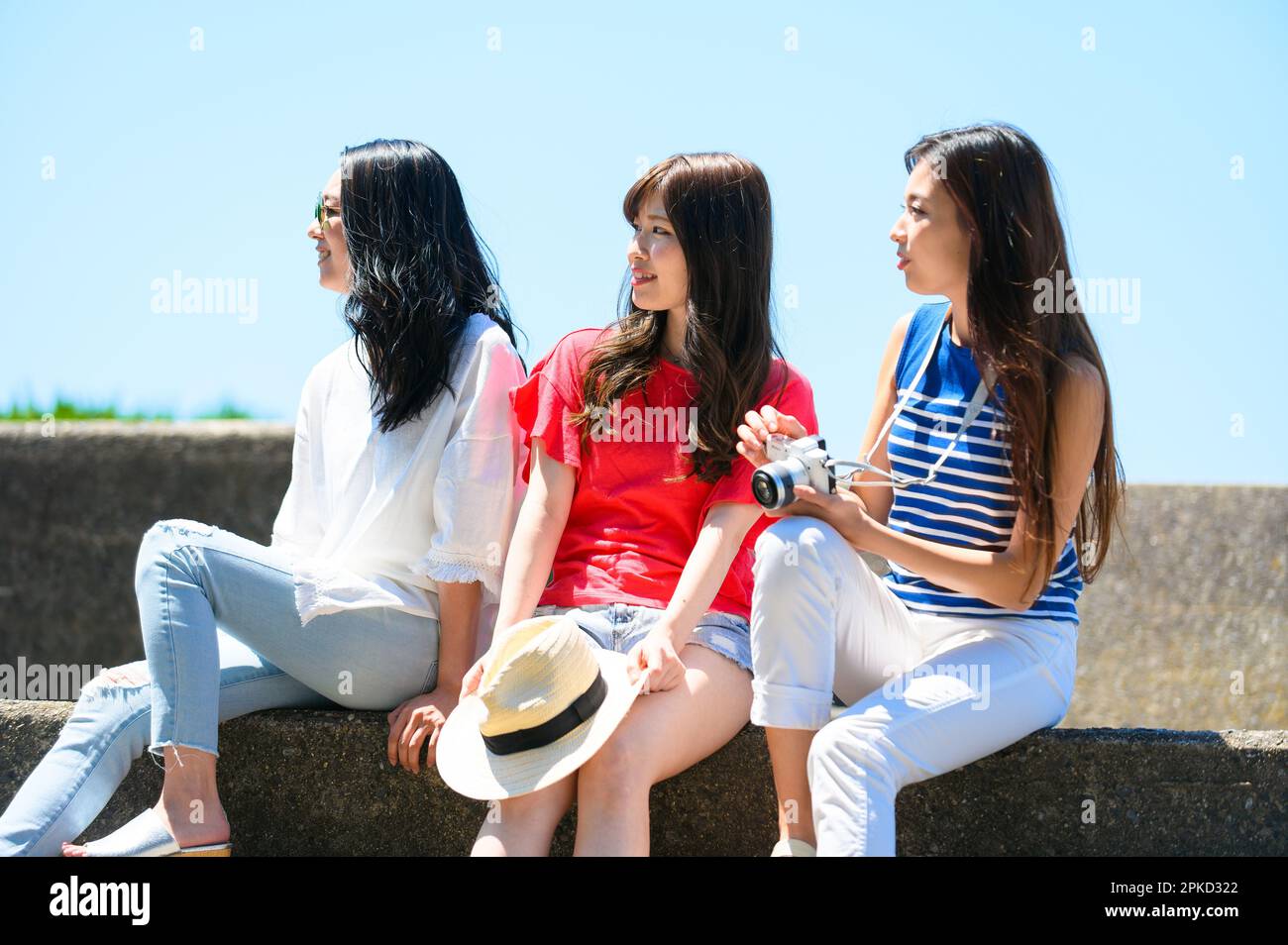 3 women traveling to the resort sitting on the sea breakwater Stock ...