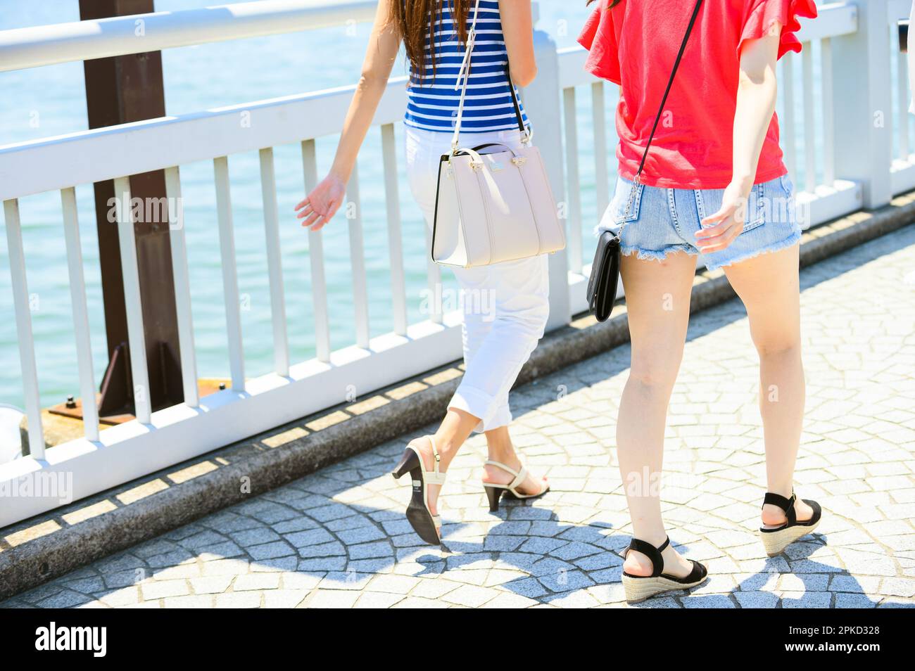 2 women traveling to a resort where they walk on a bridge over the sea ...