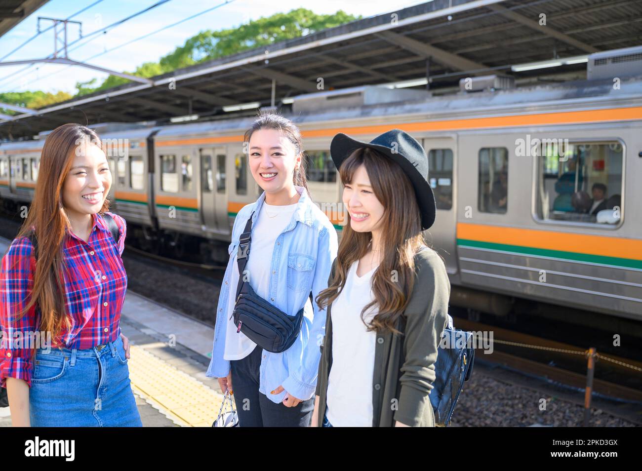 3 women on a train platform waiting for the train Stock Photo - Alamy