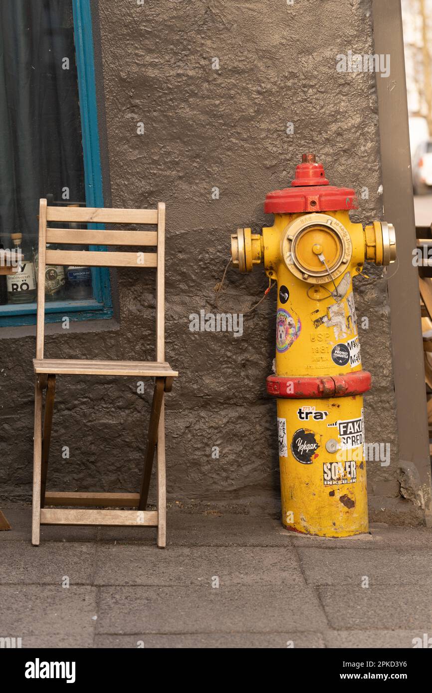 Yellow and Red Fire Hydrant covered in stickers outside a coffee shop ...