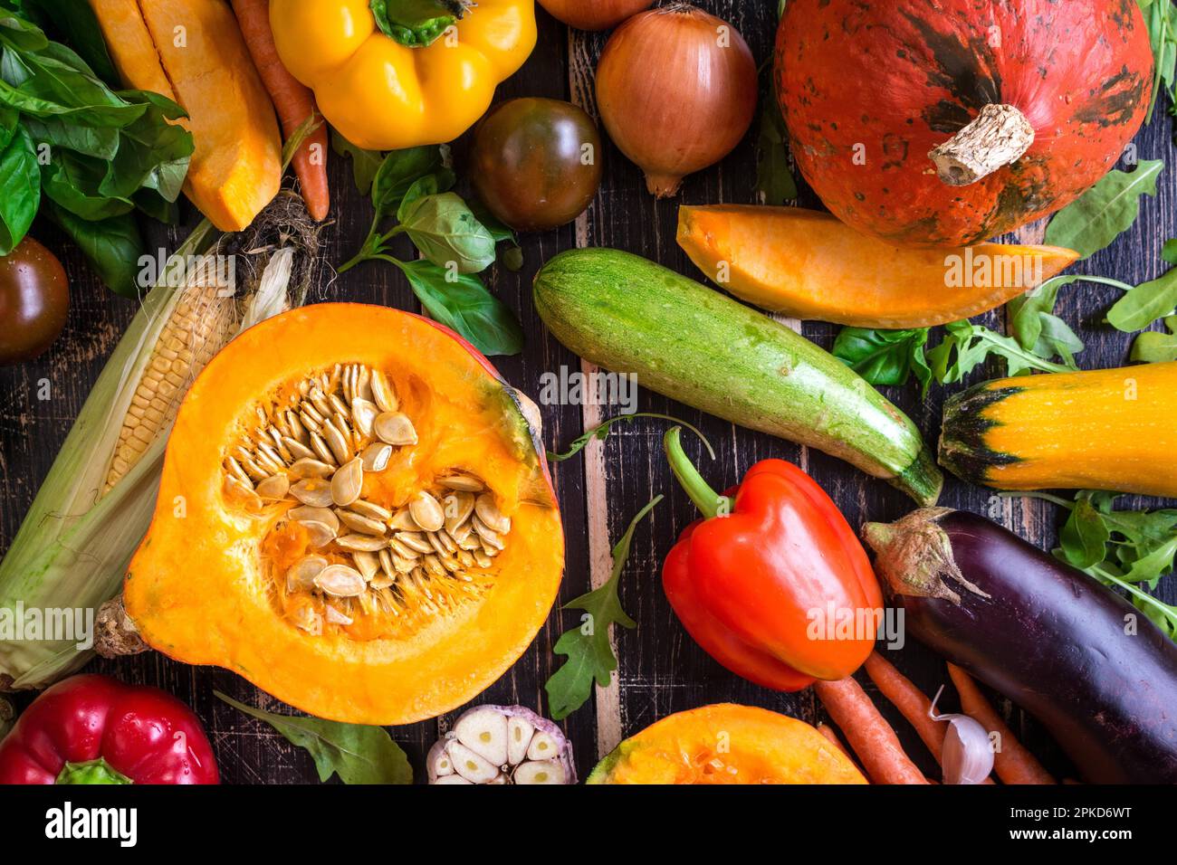 Fresh vegetables scattered on a old rustic dark textured table. Autumn ...