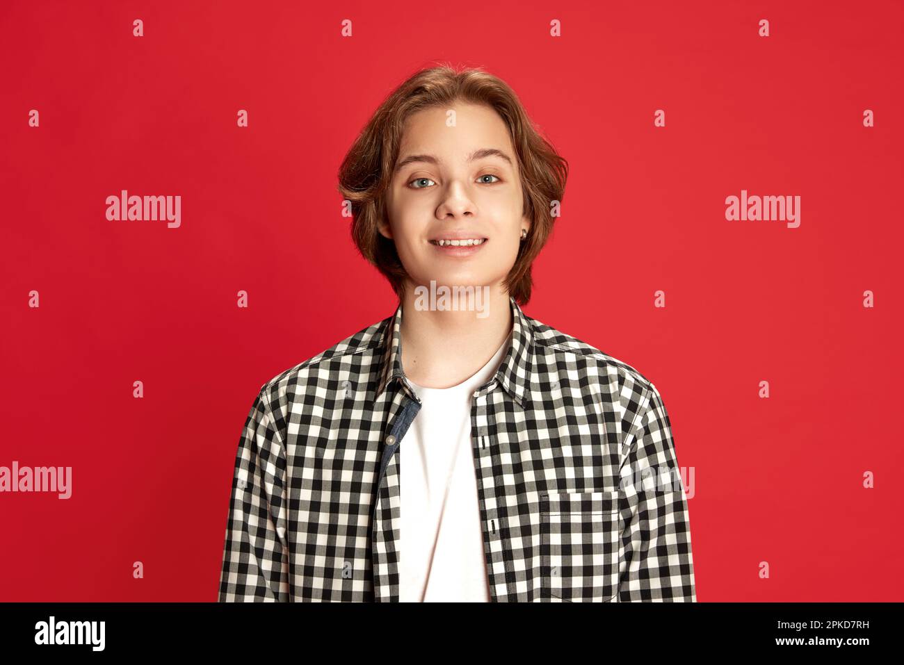 Young teen boy with long hair wearing checkered shirt looking at camera ...