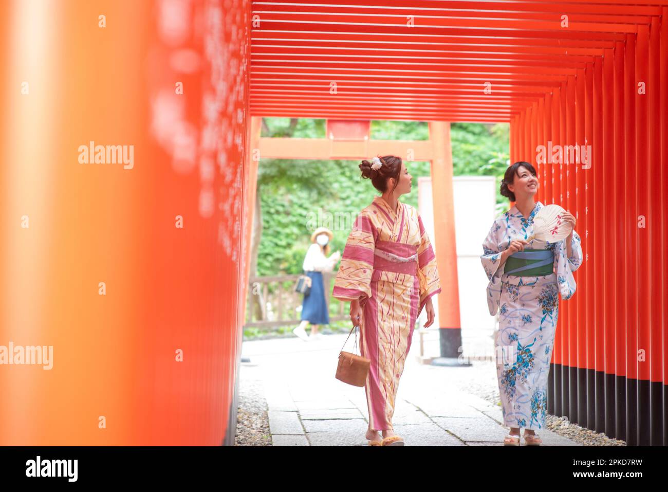 Two women in yukata passing through the torii gate of a Shinto shrine ...
