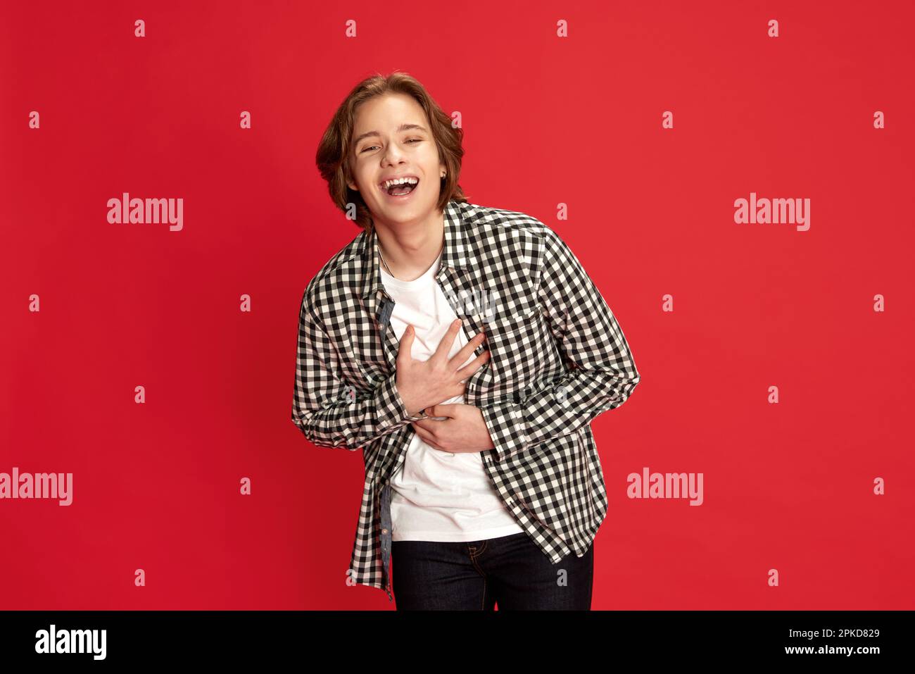 Happy young boy wearing checkered shirt and laughing at camera over red ...