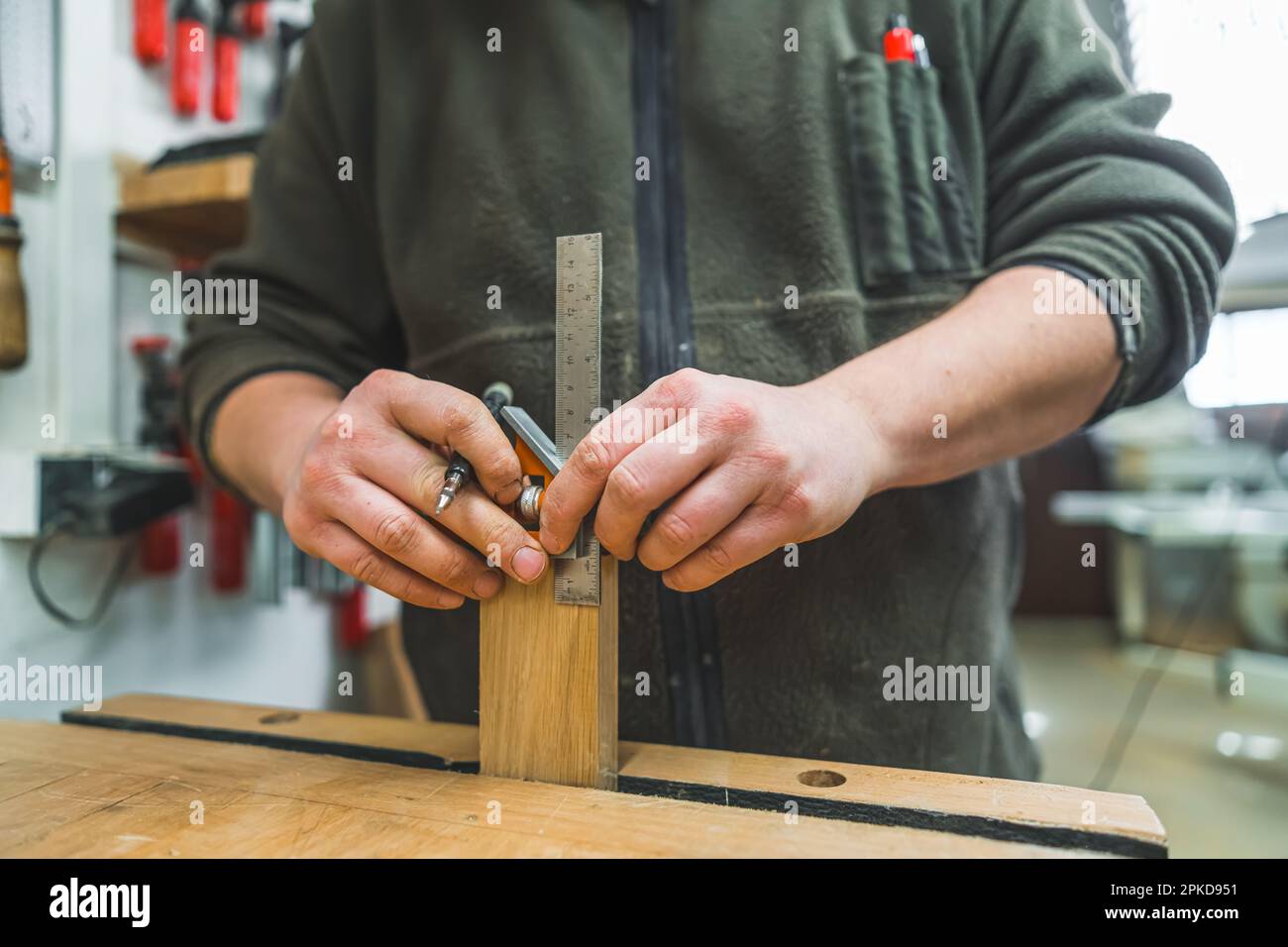Male carpenter using a pencil and metal ruler to draw a line on small ...