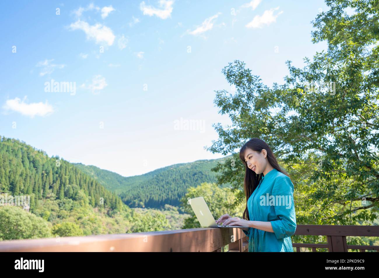 Woman working remotely from a log cabin balcony Stock Photo - Alamy