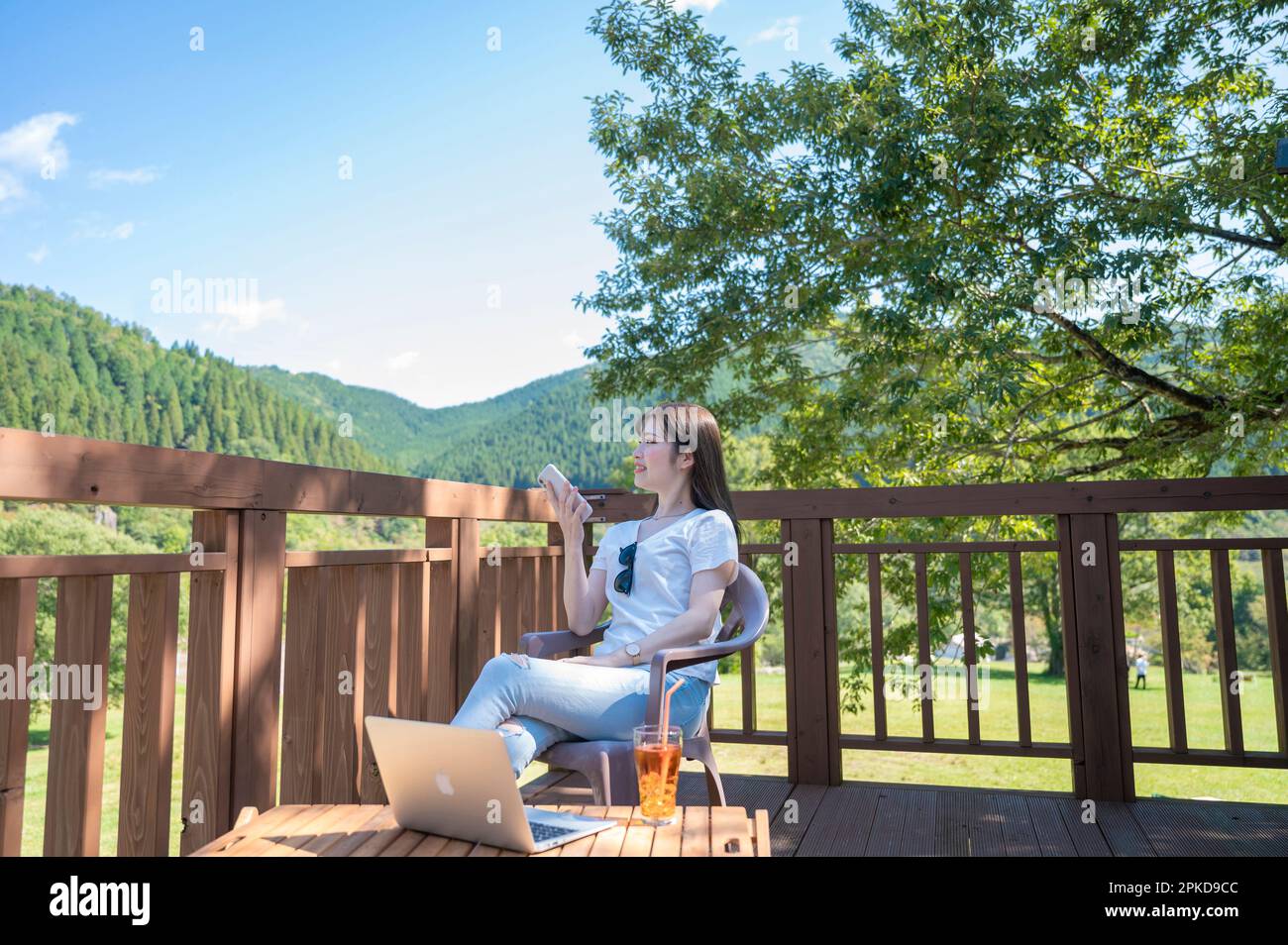 Woman working remotely from a log cabin balcony Stock Photo - Alamy