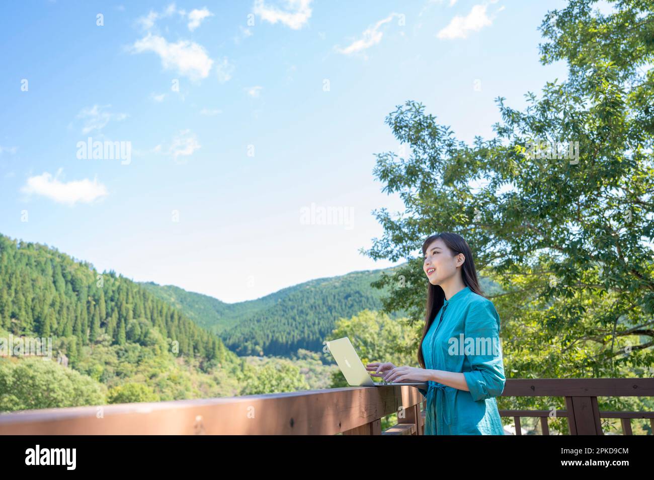 Woman working remotely from a log cabin balcony Stock Photo - Alamy
