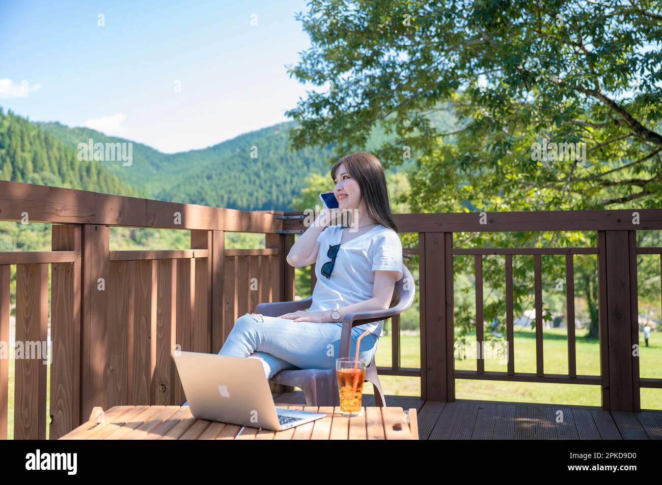 Woman working remotely from a log cabin balcony Stock Photo - Alamy