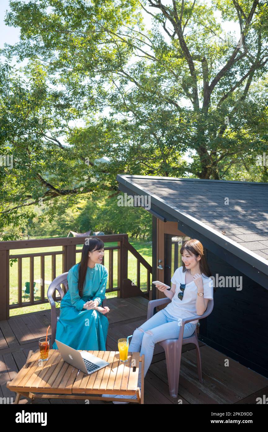 Two women chatting on the balcony of a log cabin Stock Photo - Alamy
