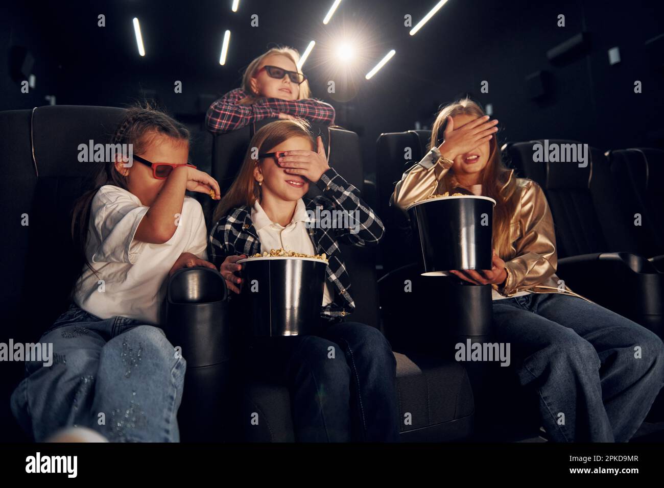 Eating popcorn. Group of kids sitting in cinema and watching movie ...