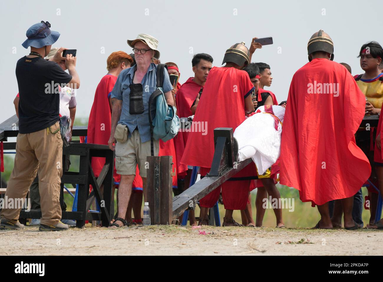 A foreigner poses beside a woman that is being nailed to the cross ...