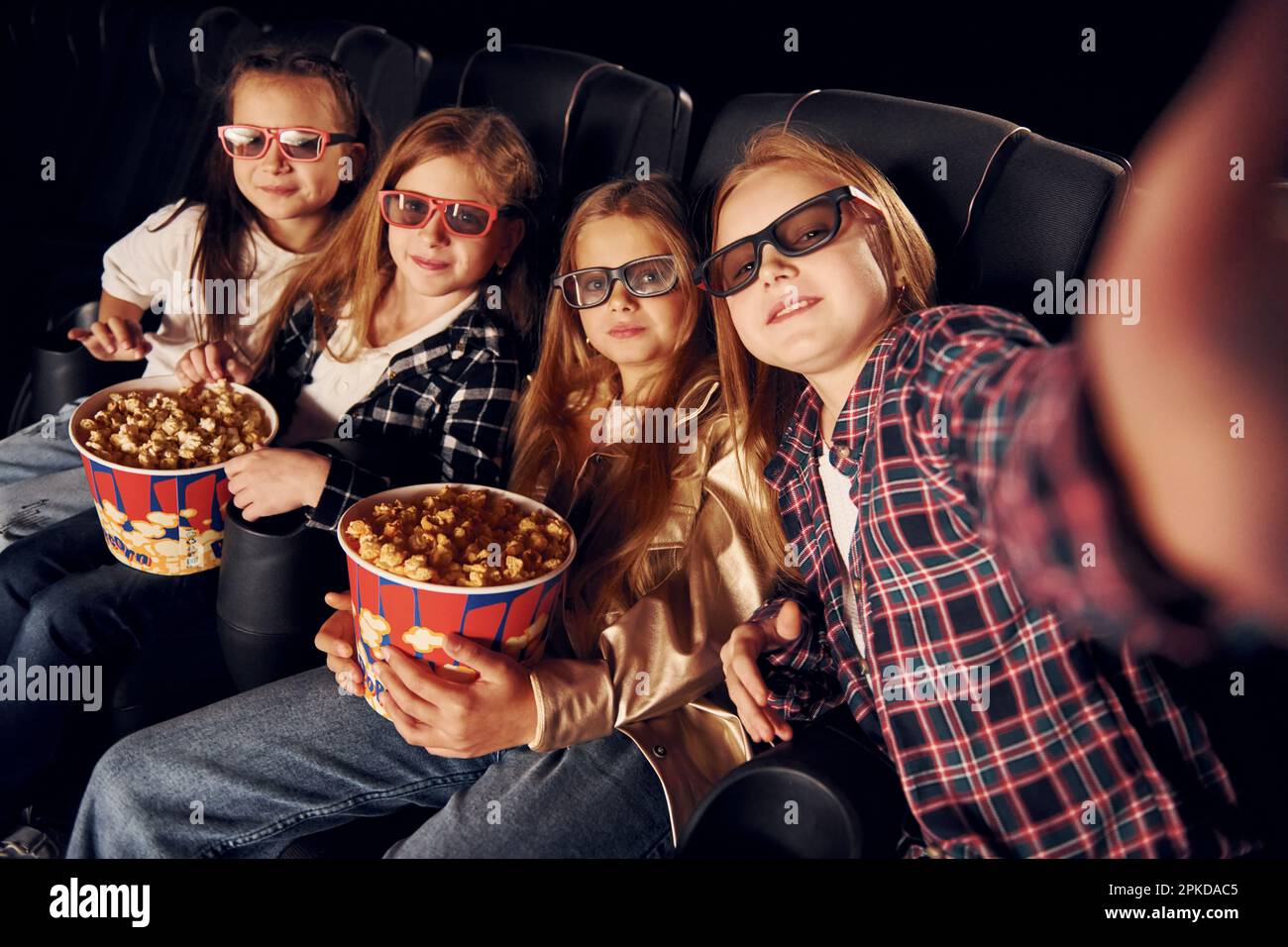 Doing selfie. Group of kids sitting in cinema and watching movie ...