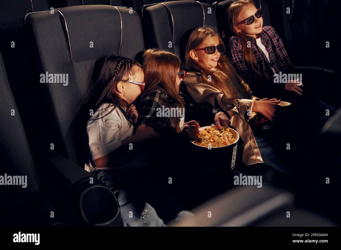 Having fun. Group of kids sitting in cinema and watching movie together ...