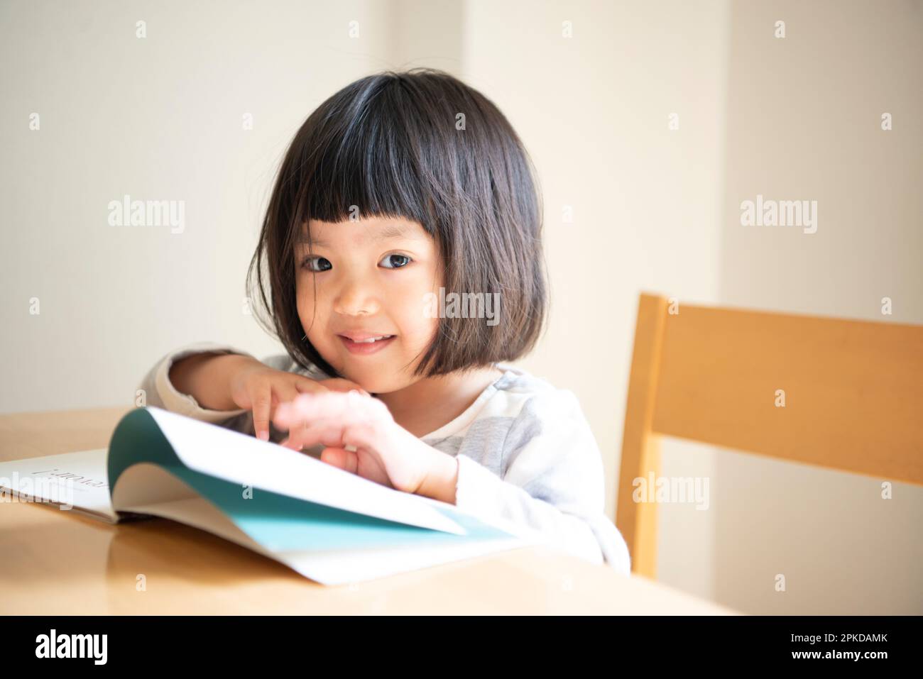 Girl laughing at the table with a picture book open Stock Photo - Alamy