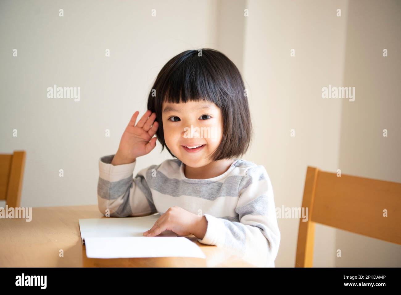 Girl at the table with a picture book open and laughing Stock Photo - Alamy