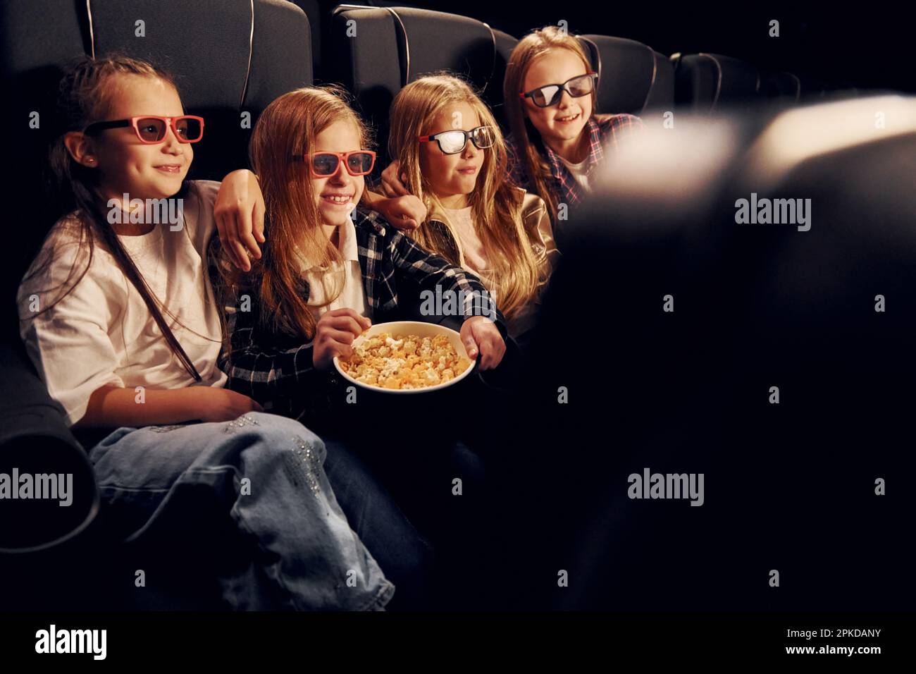 Weekend fun. Group of kids sitting in cinema and watching movie ...
