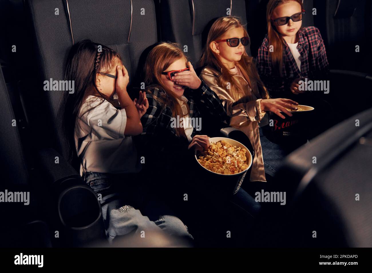 Having fun. Group of kids sitting in cinema and watching movie together ...