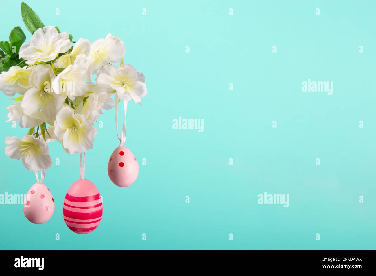 Three Easter eggs in shades of pink hanging from a branch in full bloom ...