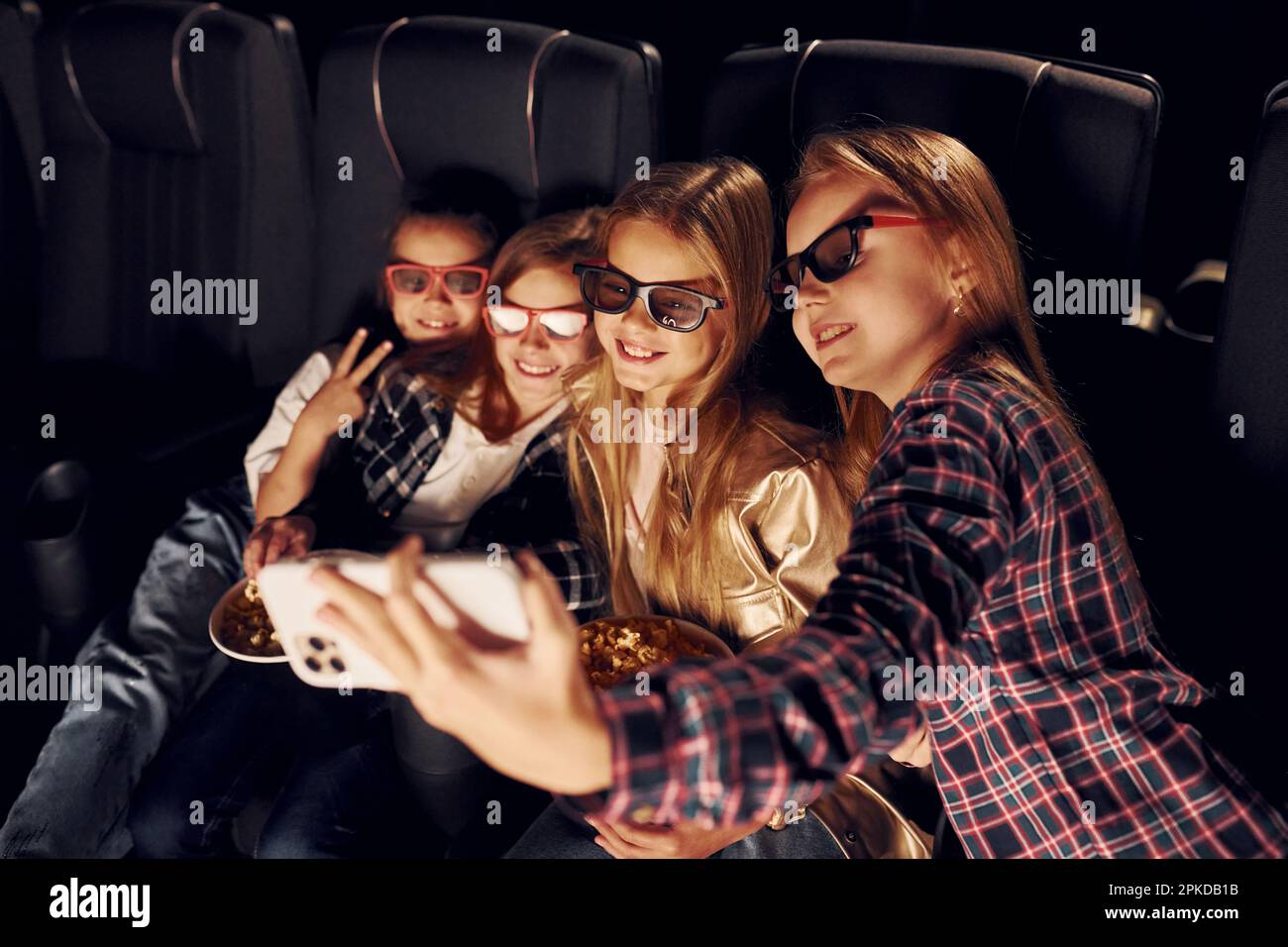 Relaxing and having fun. Group of kids sitting in cinema and watching ...