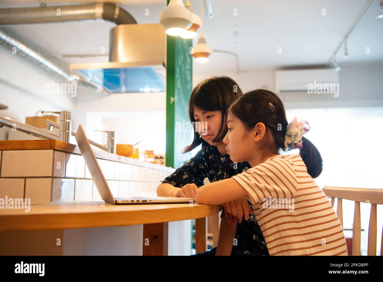 Sisters looking at a computer screen Stock Photo - Alamy