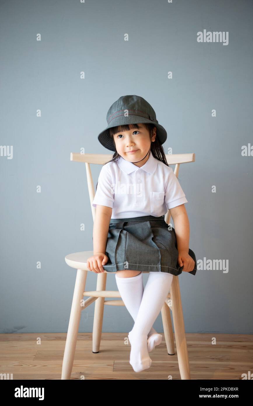 Kindergartner in uniform sitting on a chair Stock Photo - Alamy