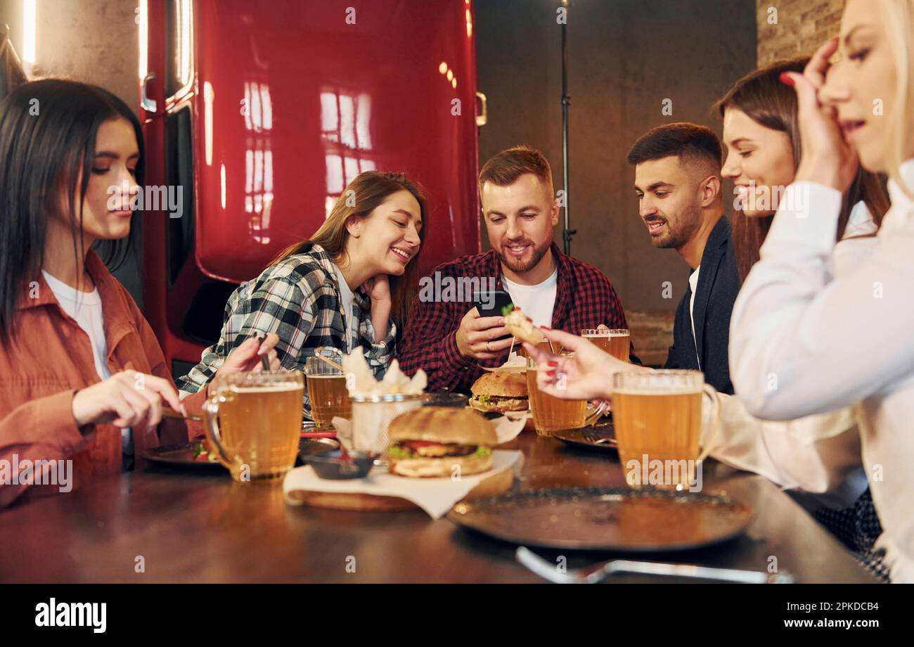 Modern interior. Group of young friends sitting together in bar with ...