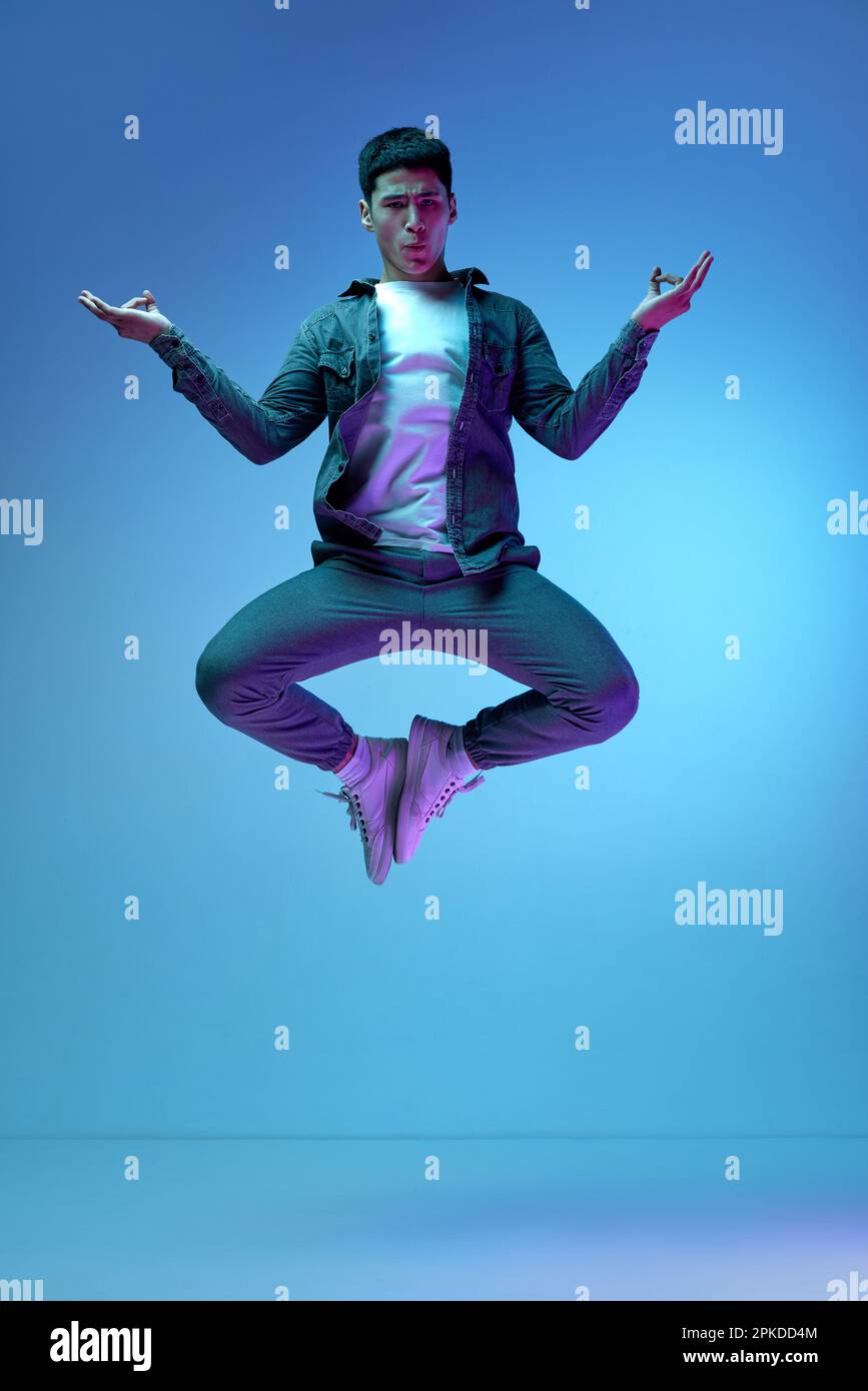 Relaxation, calming down. Young emotive man in casual clothes jumping ...