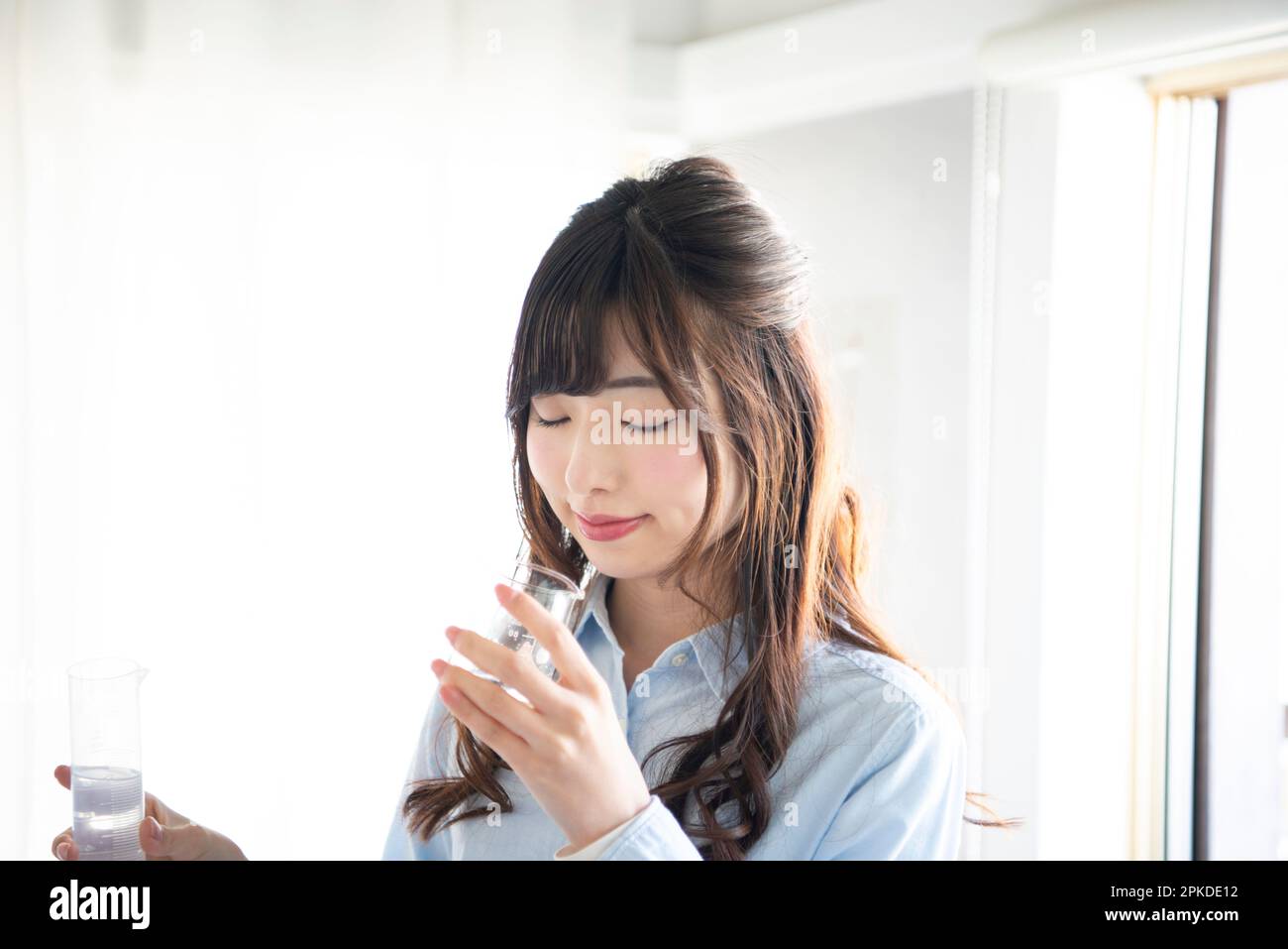 Woman smelling aroma oil from a beaker Stock Photo - Alamy
