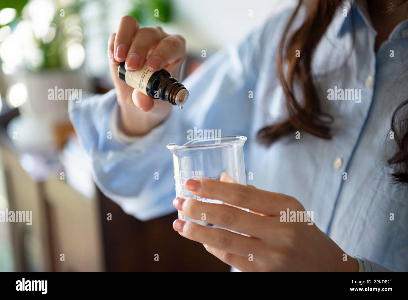 Woman dripping aroma oil into a beaker Stock Photo - Alamy