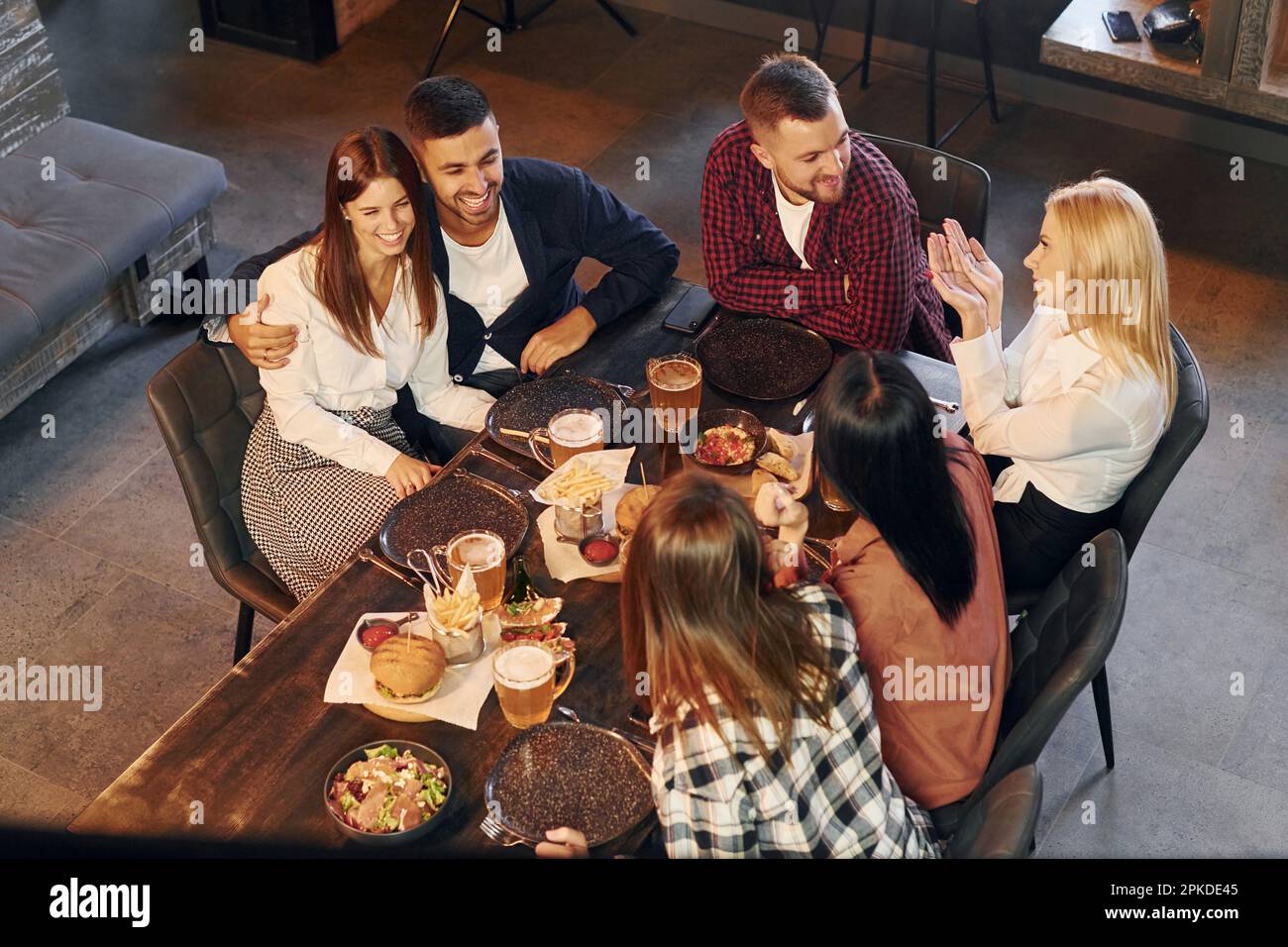 Eating and drinking. Group of young friends sitting together in bar ...