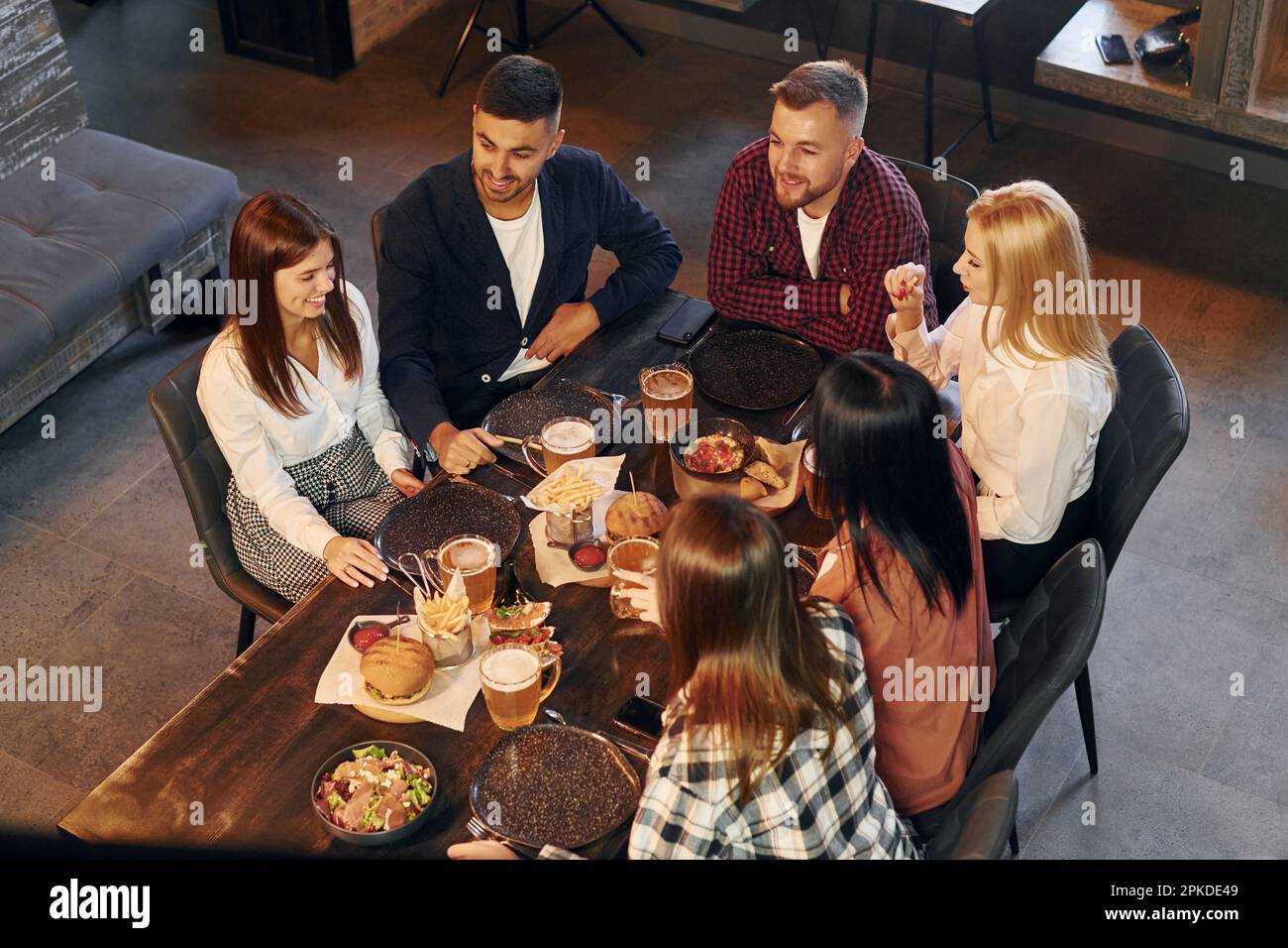 Eating and drinking. Group of young friends sitting together in bar ...